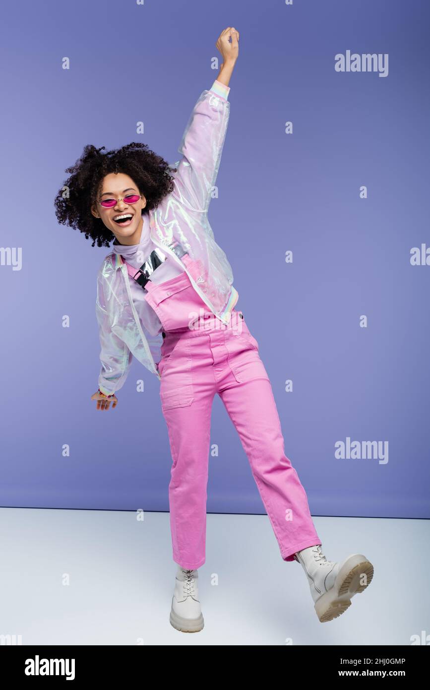 full length of excited african american woman in stylish overalls and ...