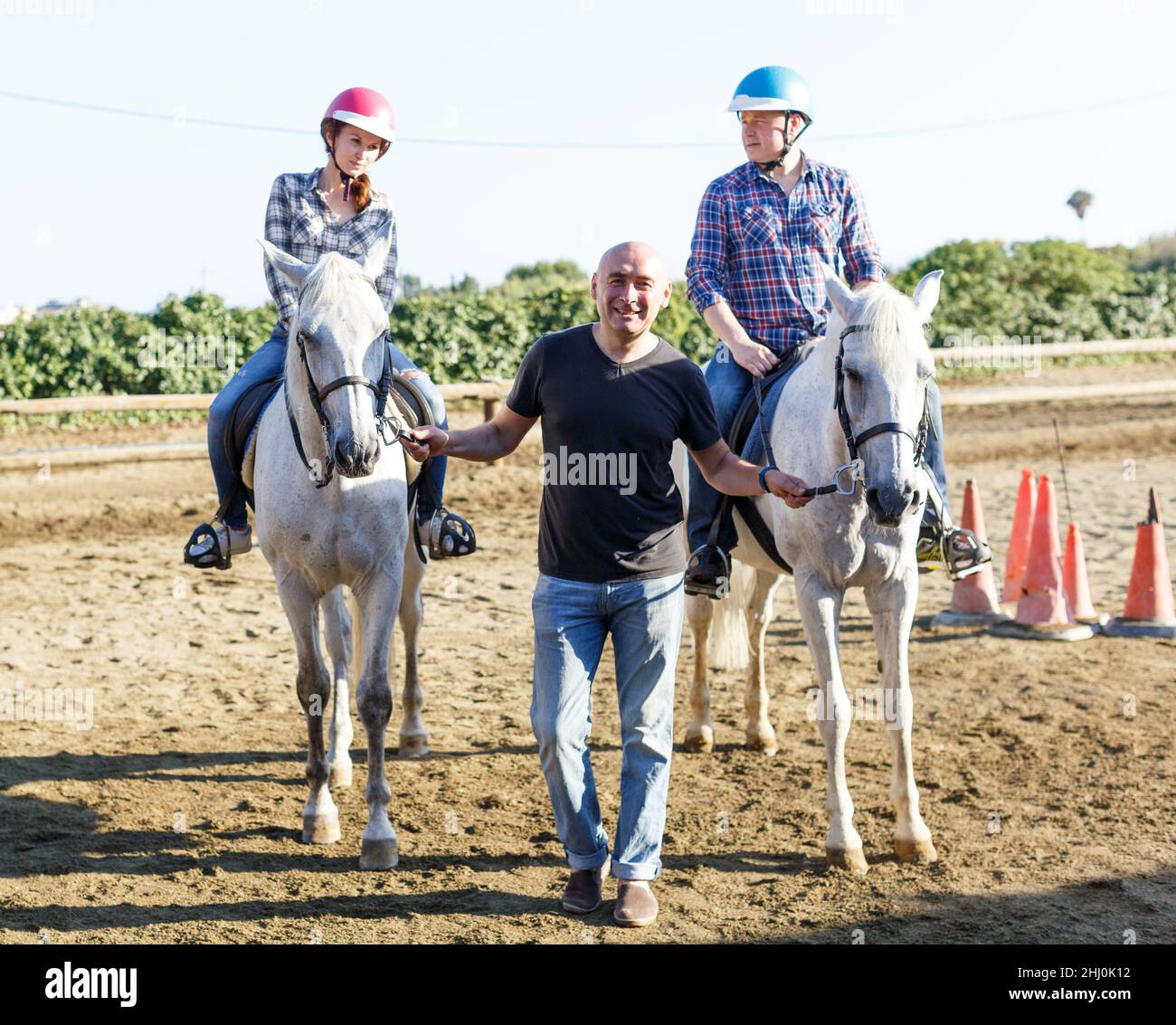 Woman and man with trainer riding horse at farm at summer day Stock ...