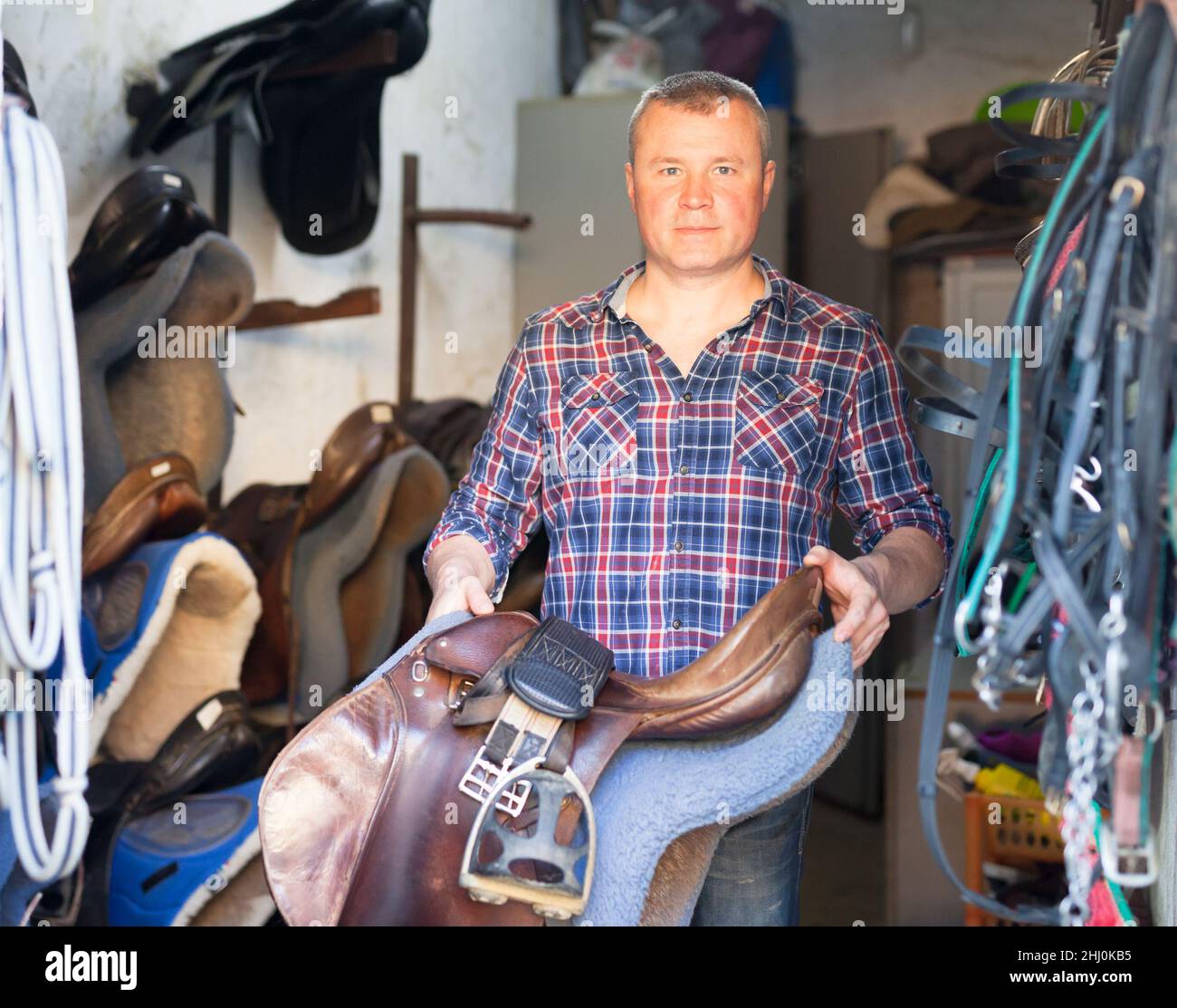 Portrait of man farmer with seats standing at horse stable Stock Photo ...