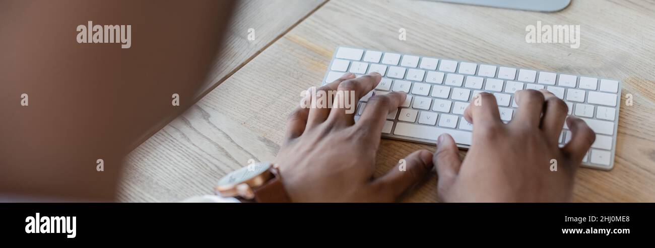 cropped view of african american man typing on computer keyboard ...