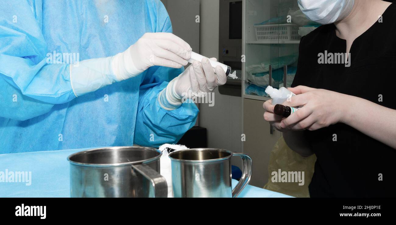 Hands of a doctor filling a syringe with medicine. Hands of surgeons in ...