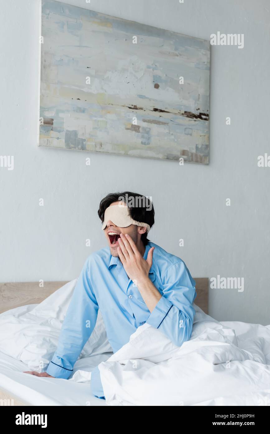 awakened man in sleep mask yawning on bed in morning Stock Photo - Alamy
