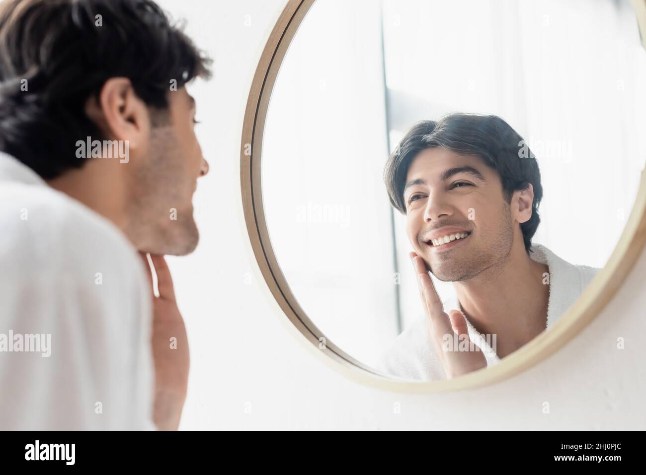 happy man looking in mirror and touching face in bathroom Stock Photo ...