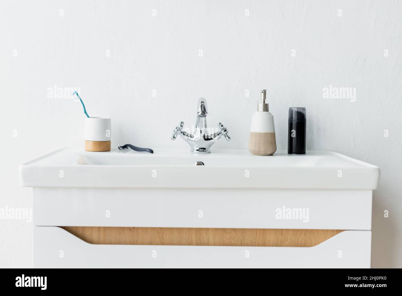 white sink with faucet, dispenser with liquid soap, shaving foam ...