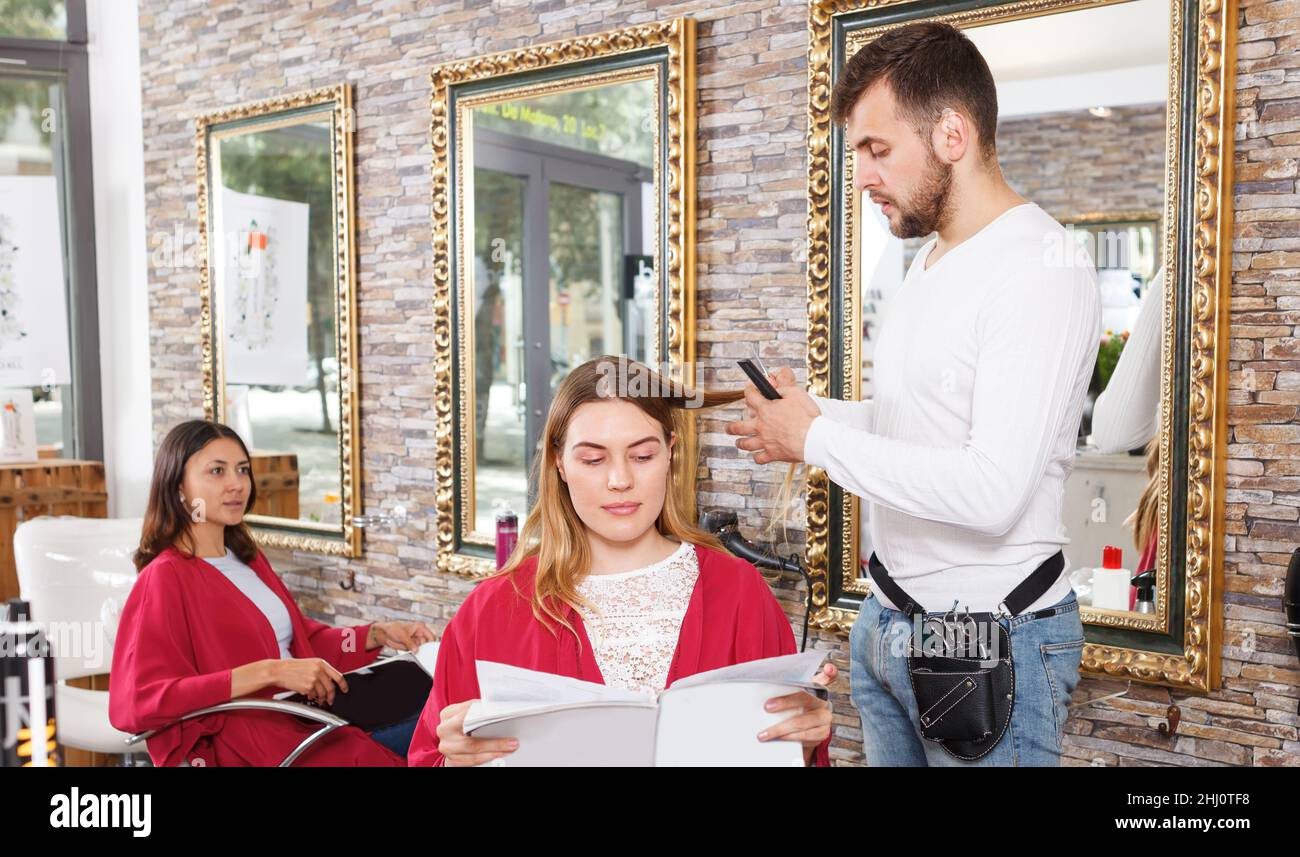 Positive guy hairdresser working with woman hair in salon Stock Photo ...