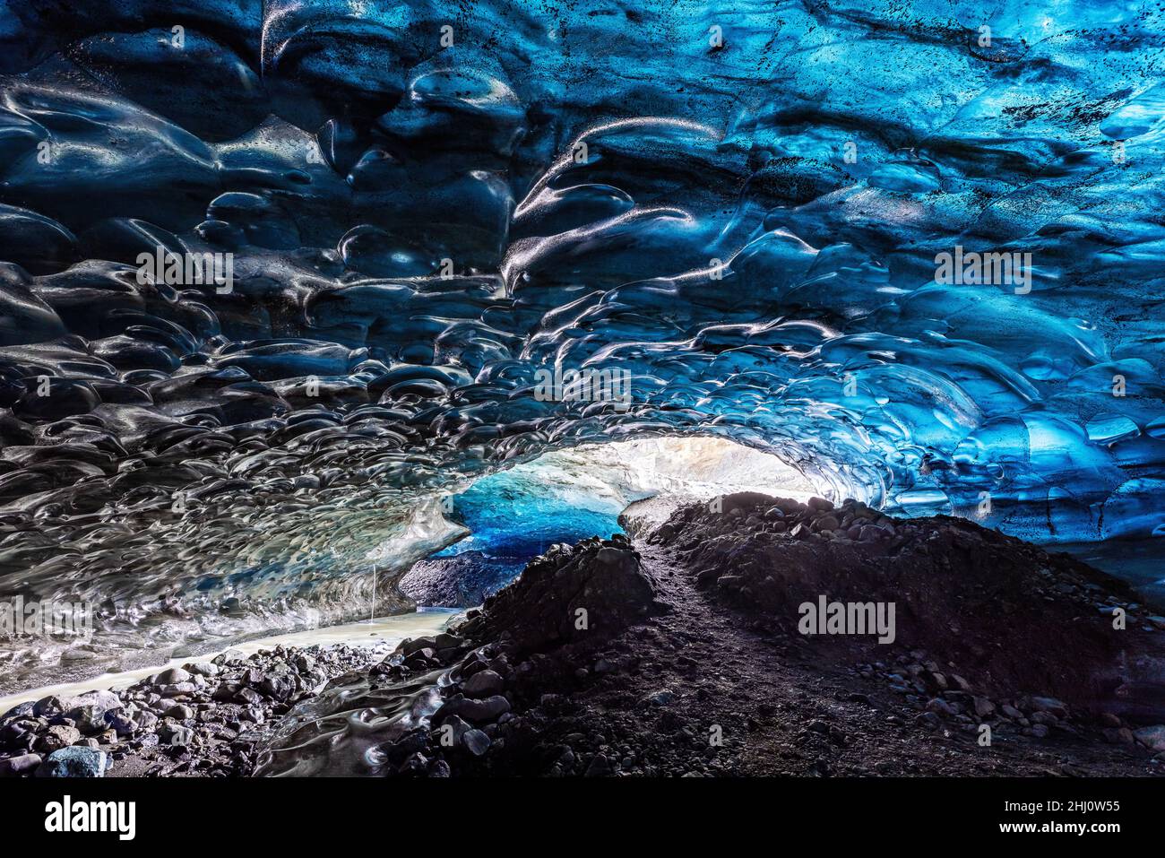 An icy river carries melt water through an ice cave in the glacier ...