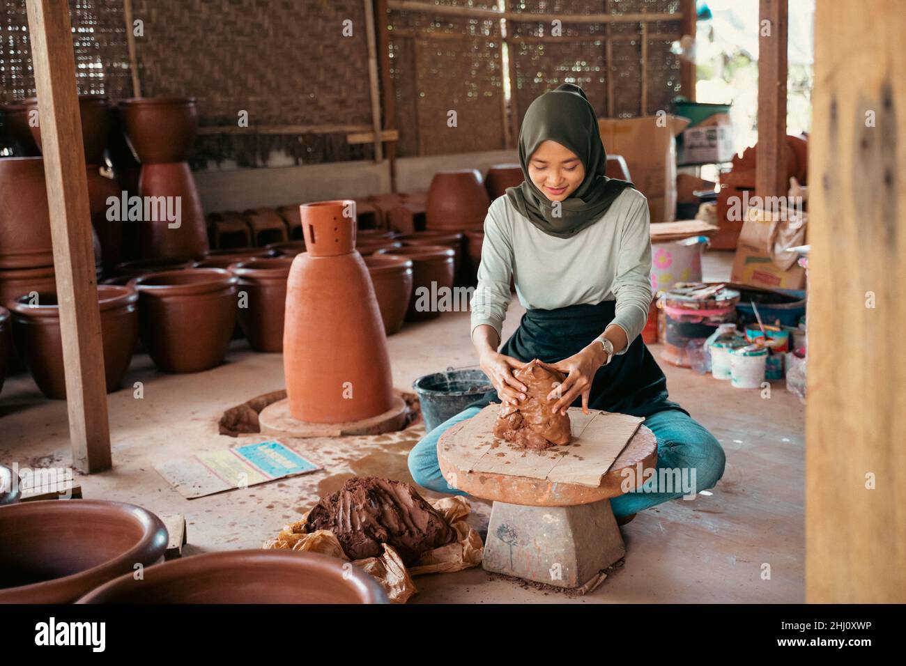 veiled girl making clay pottery on wheels in studio workshop Stock ...