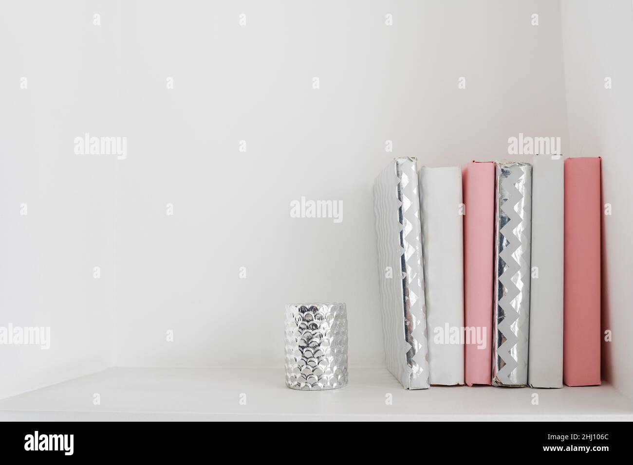 Stack of white and pink books staying on a shelf and white wall as ...