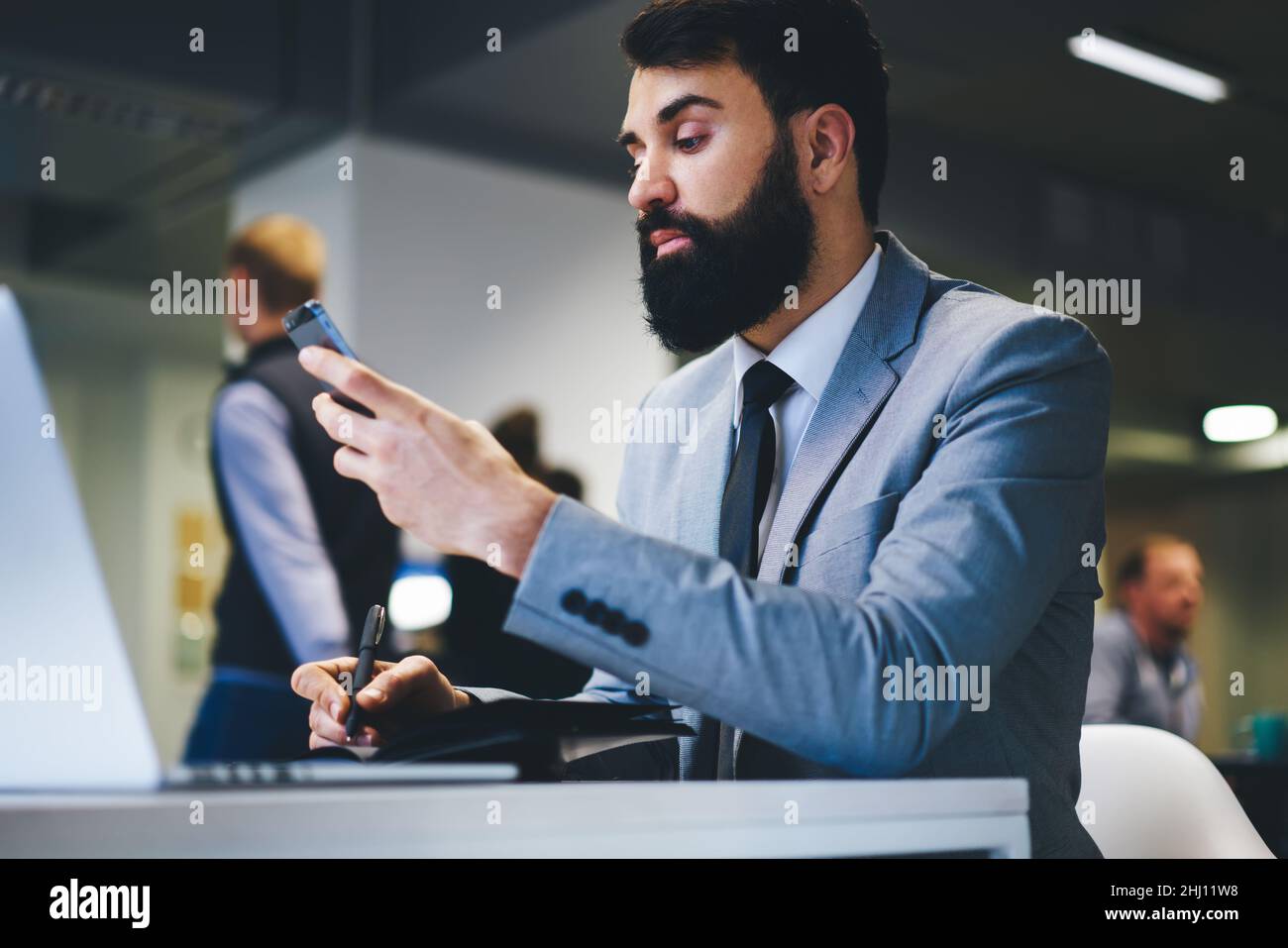 Thoughtful office worker using smartphone Stock Photo - Alamy