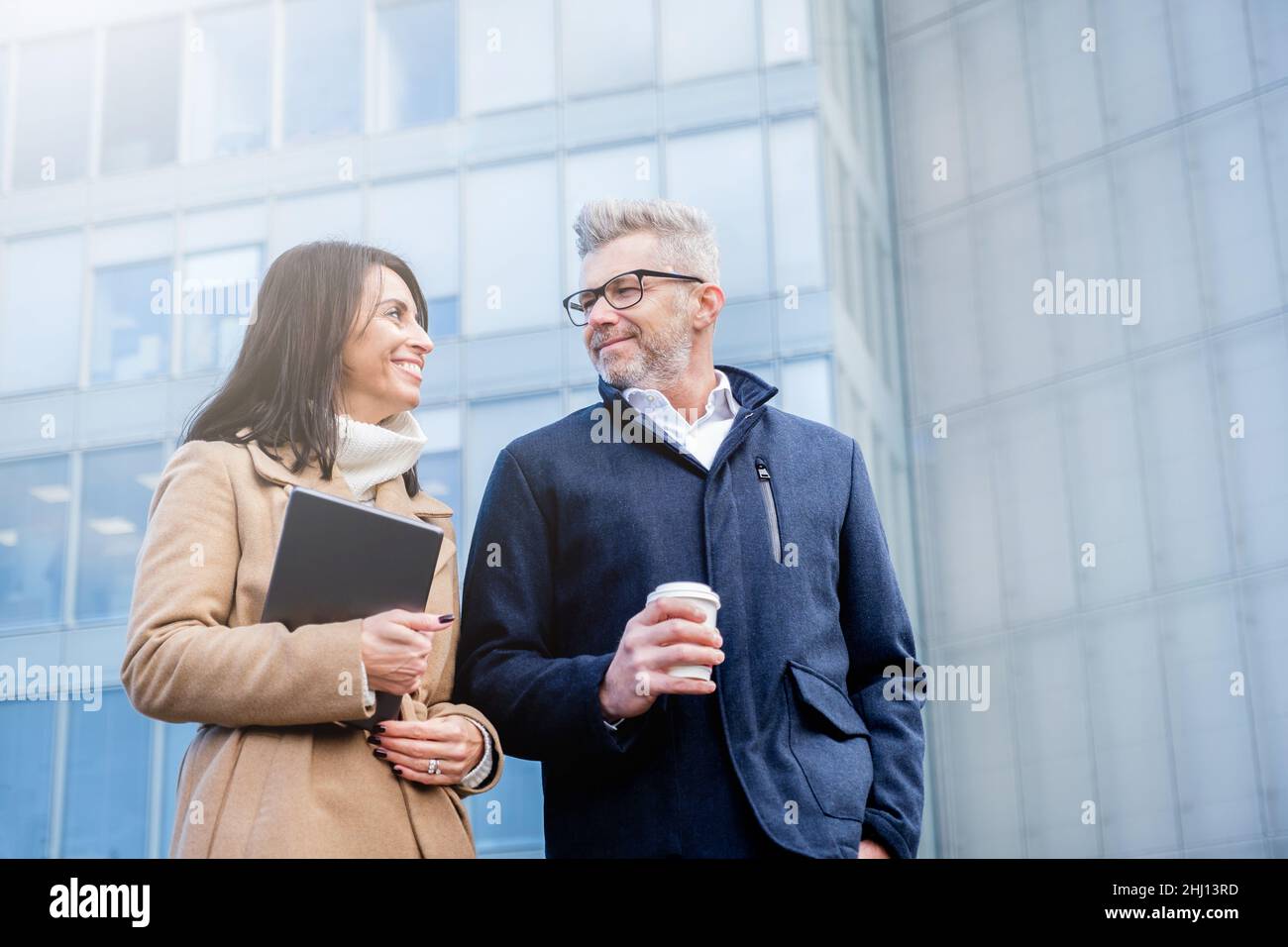 Two business people walking and discussing outdoor of a business office ...