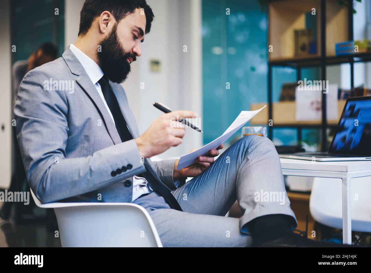 Serious entrepreneur reading documents in modern workspace Stock Photo ...