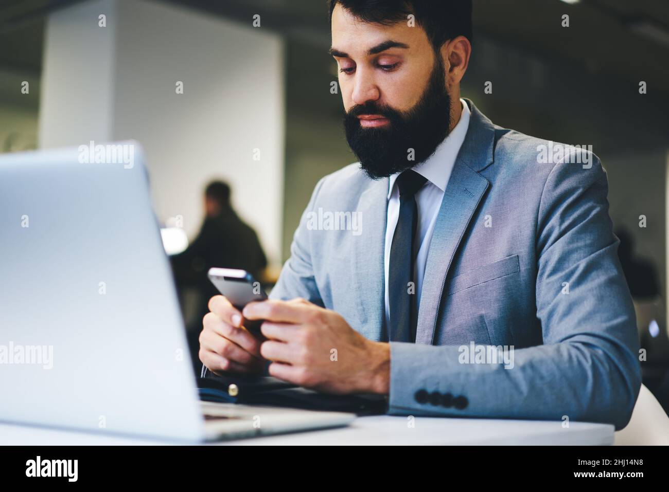Serious businessman using smartphone during work Stock Photo - Alamy
