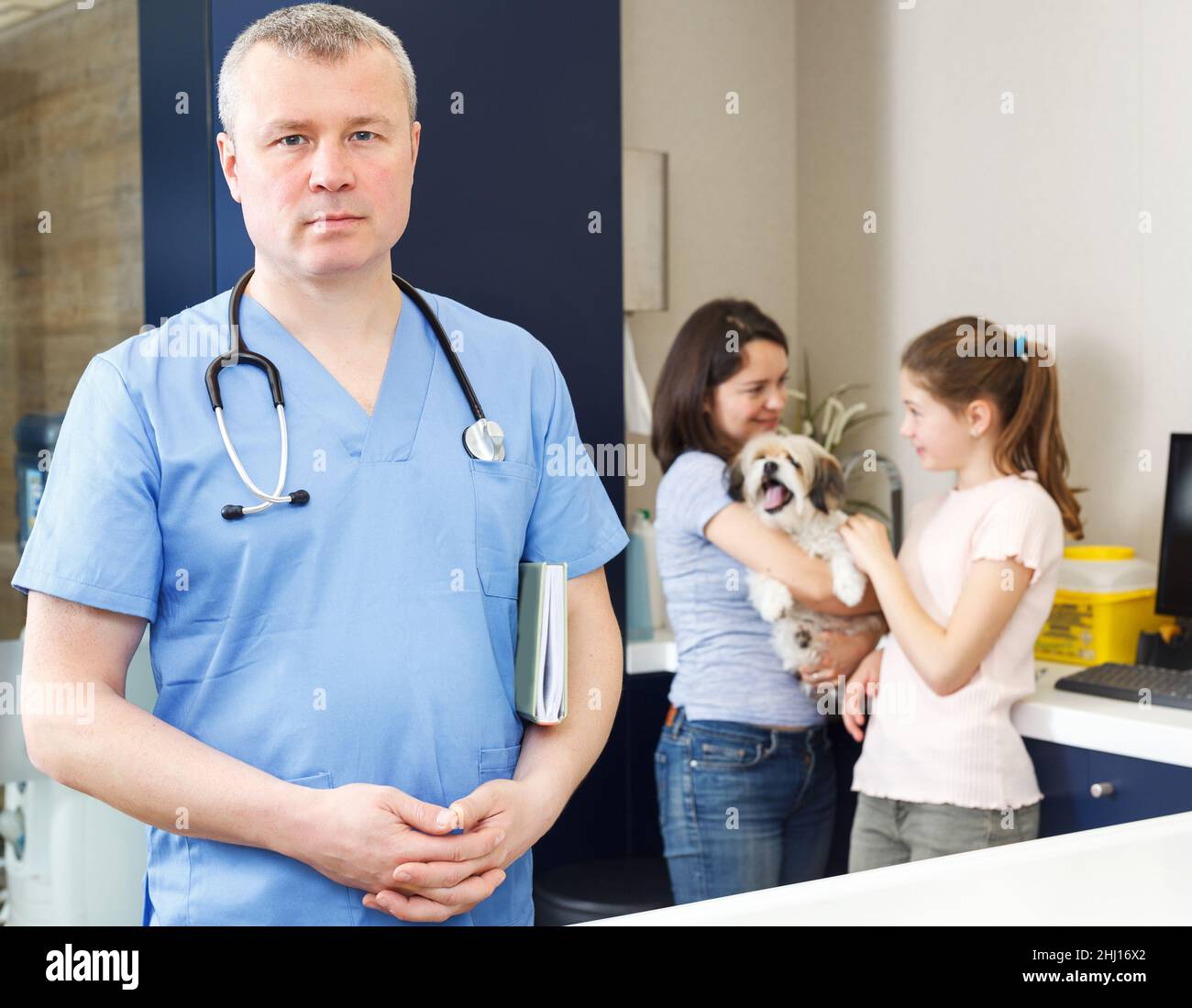 veterinarian posing at modern vet clinic with visitors behind Stock ...