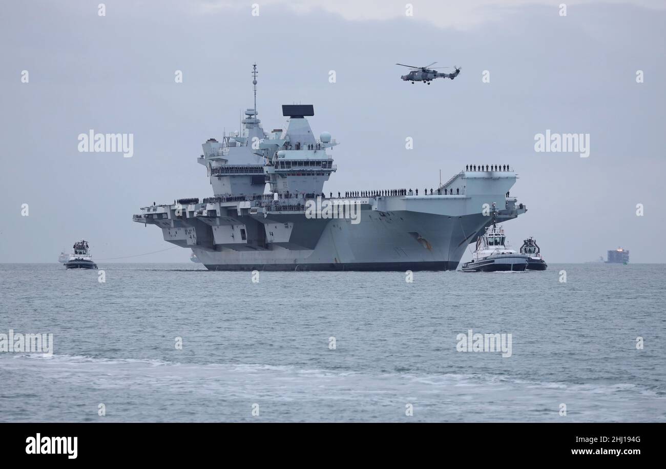 A Royal Navy Wildcat helicopter passes over the aircraft carrier HMS ...