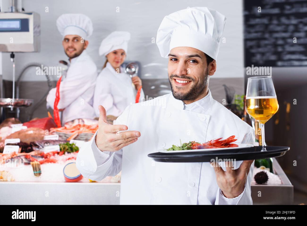 Portrait of professional chef with serving tray offering seafood Stock ...