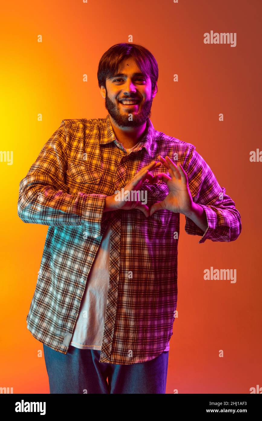 Cropped portrait of young smiling boy holding hands in heart shape and ...