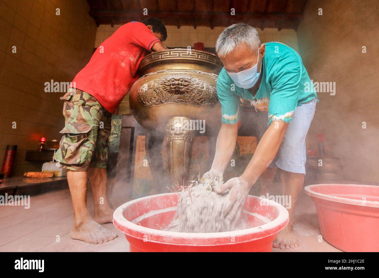 Workers lift ashes during ash sifting ritual upcoming of the Lunar New ...