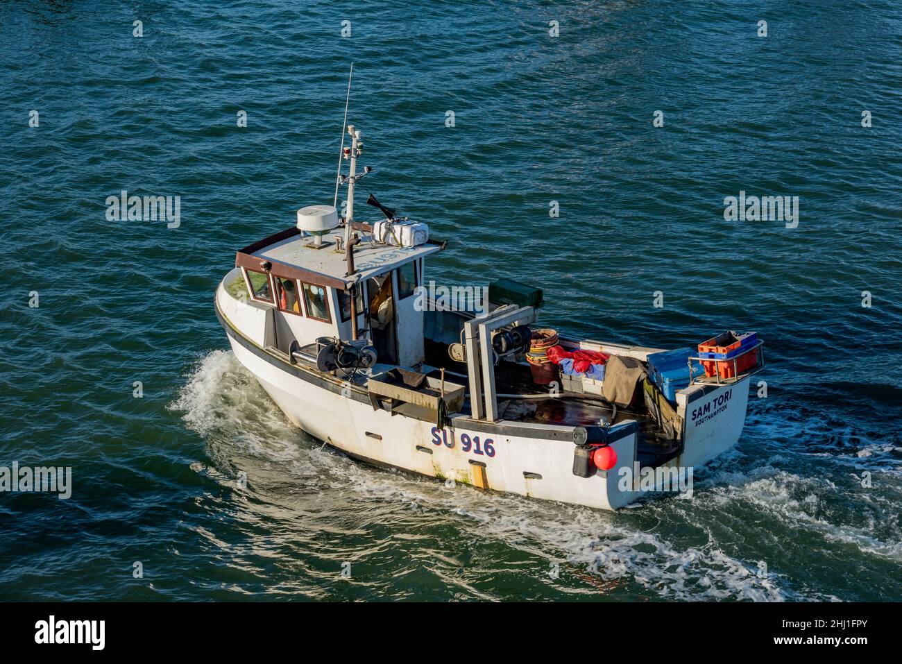 small inshore trawler or fishing boat underway with colourful nets and ...