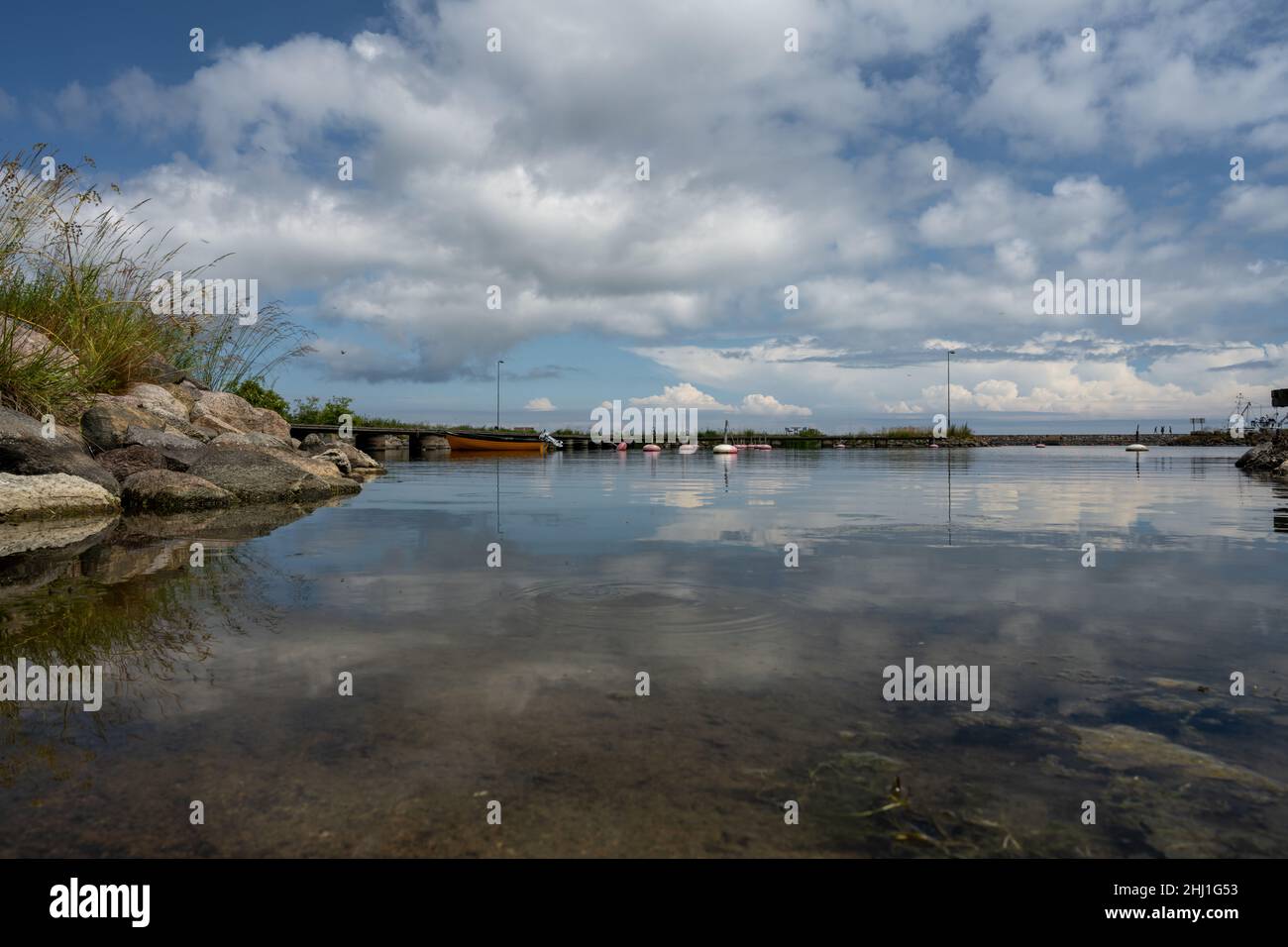 A blue sky with patchy clouds over a calm bay in the summertime. From ...