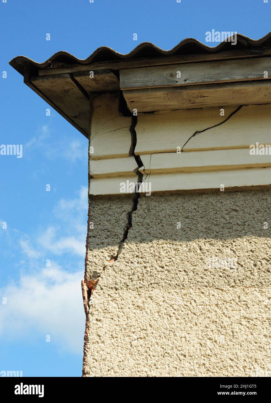 Damaged house stucco wall corner. Cracked Wall near Roof Construction ...