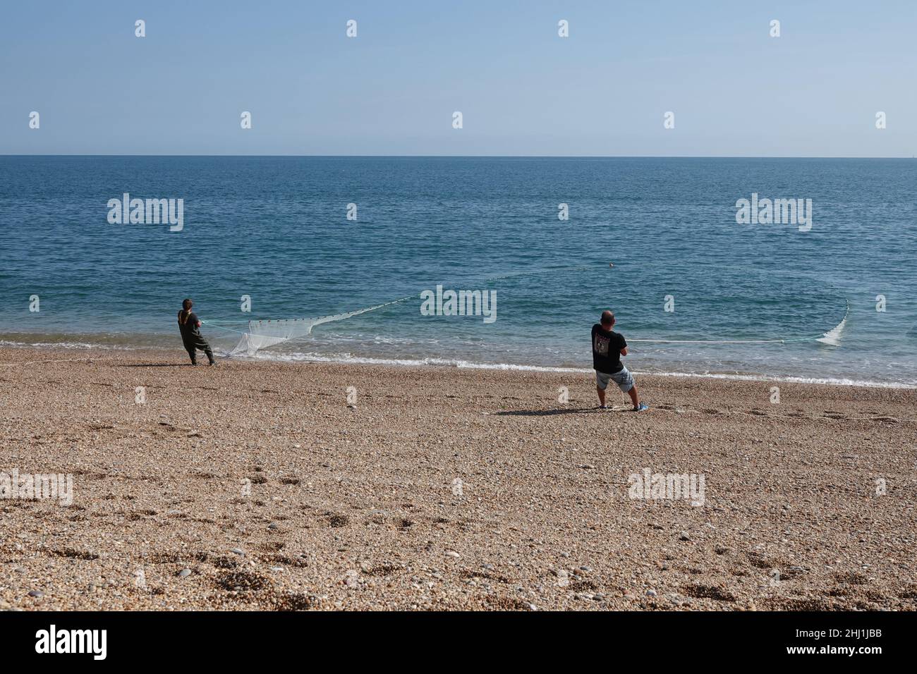 Two men fishing with a net from the shore Stock Photo - Alamy