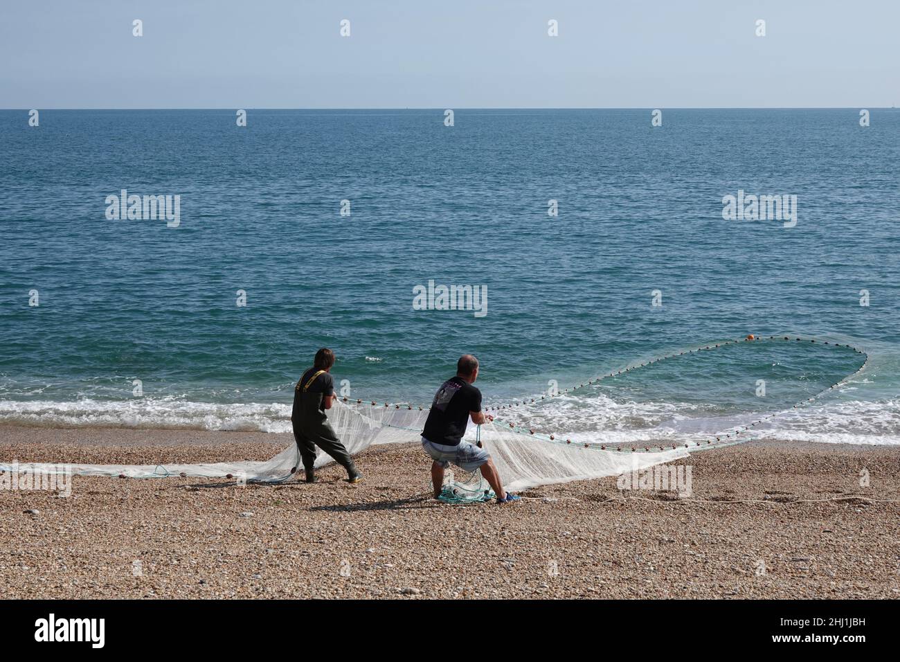 Two men fishing with a net from the shore Stock Photo - Alamy