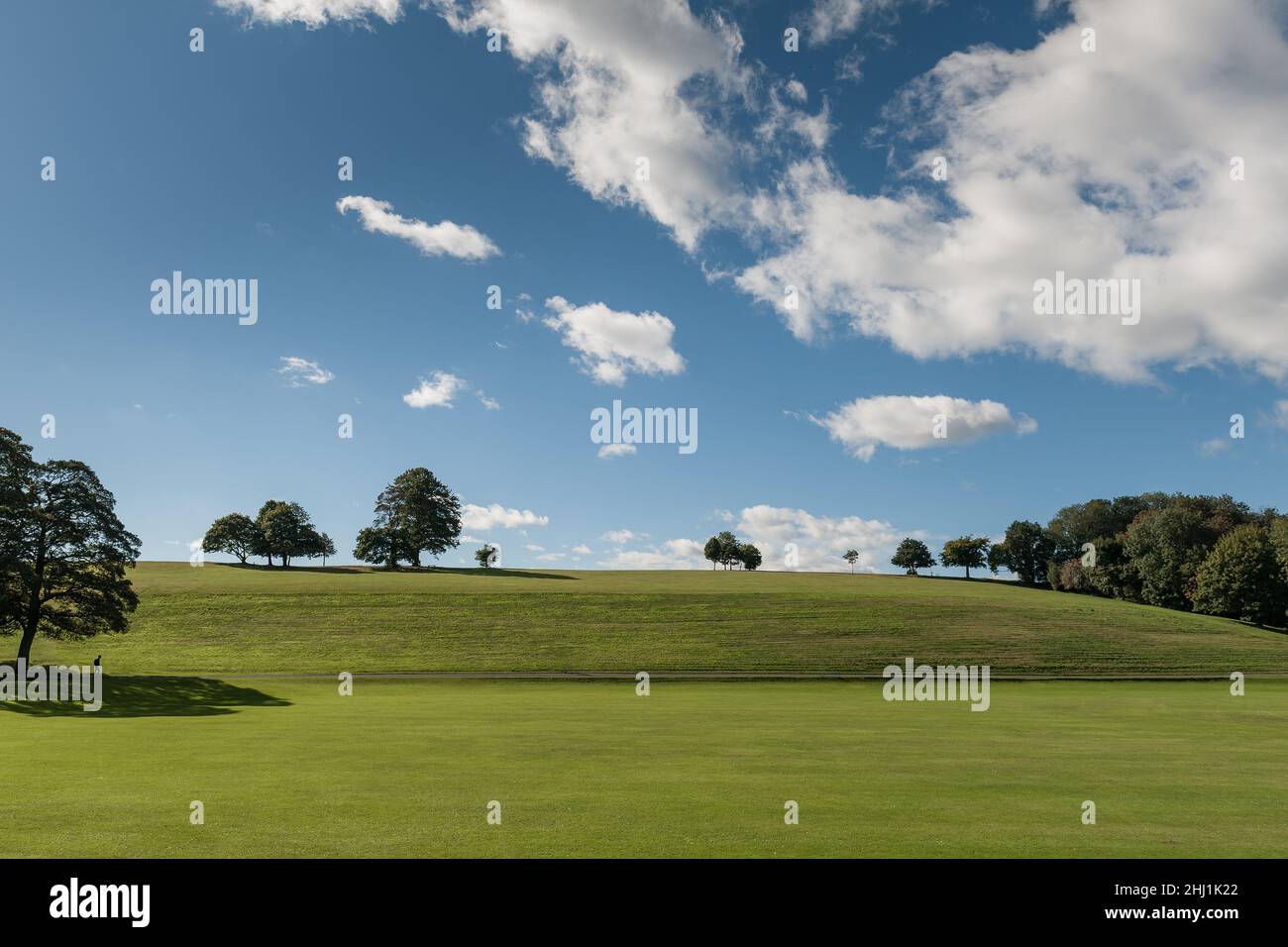 Minute isolated person takes a stroll through beautiful rolling park ...