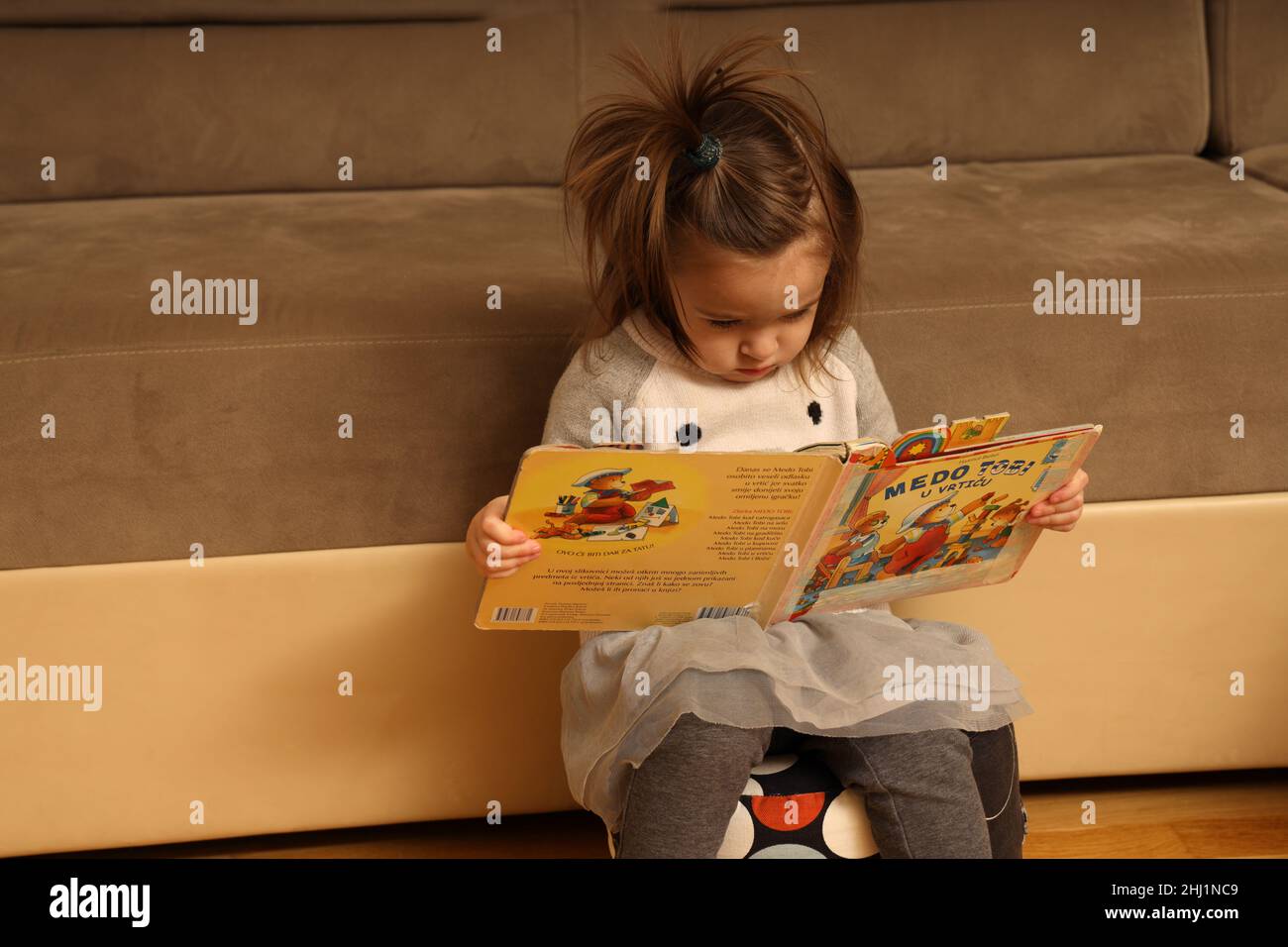 One little kid girl reading at home on the couch Stock Photo - Alamy