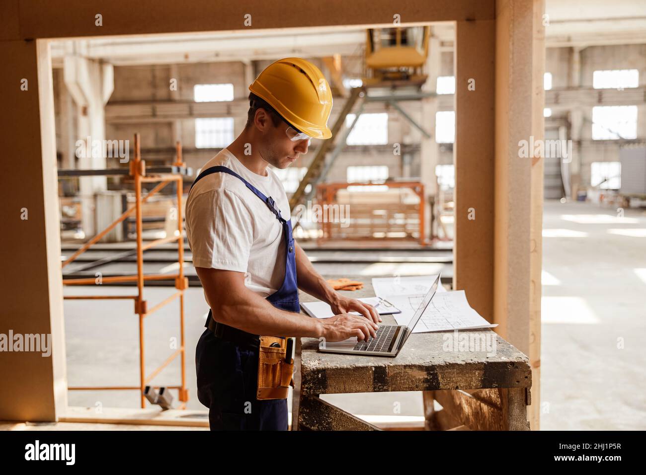 Male builder using modern laptop at work Stock Photo - Alamy