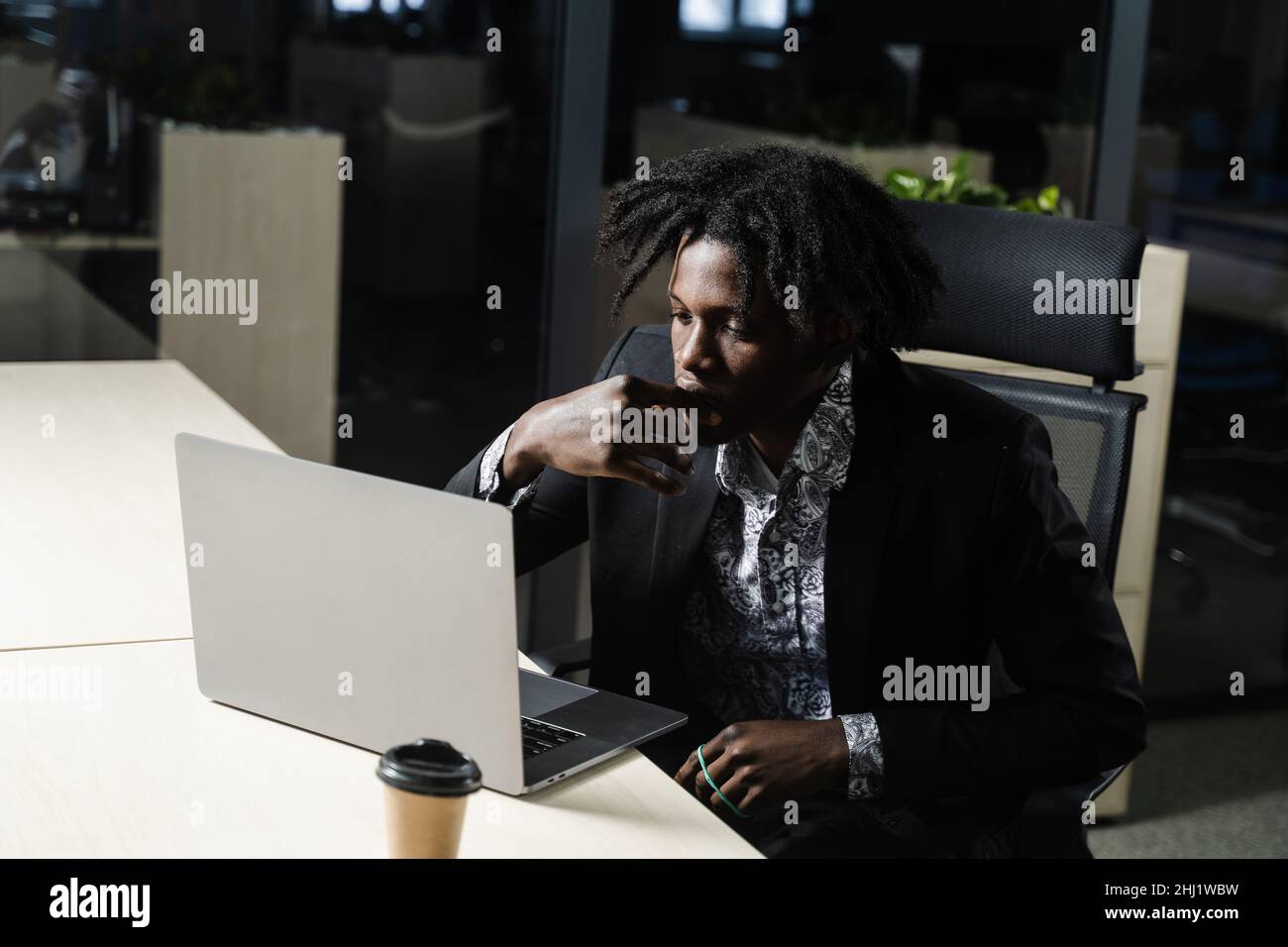 Black IT programmer is working on laptop in coworking space. Handsome ...