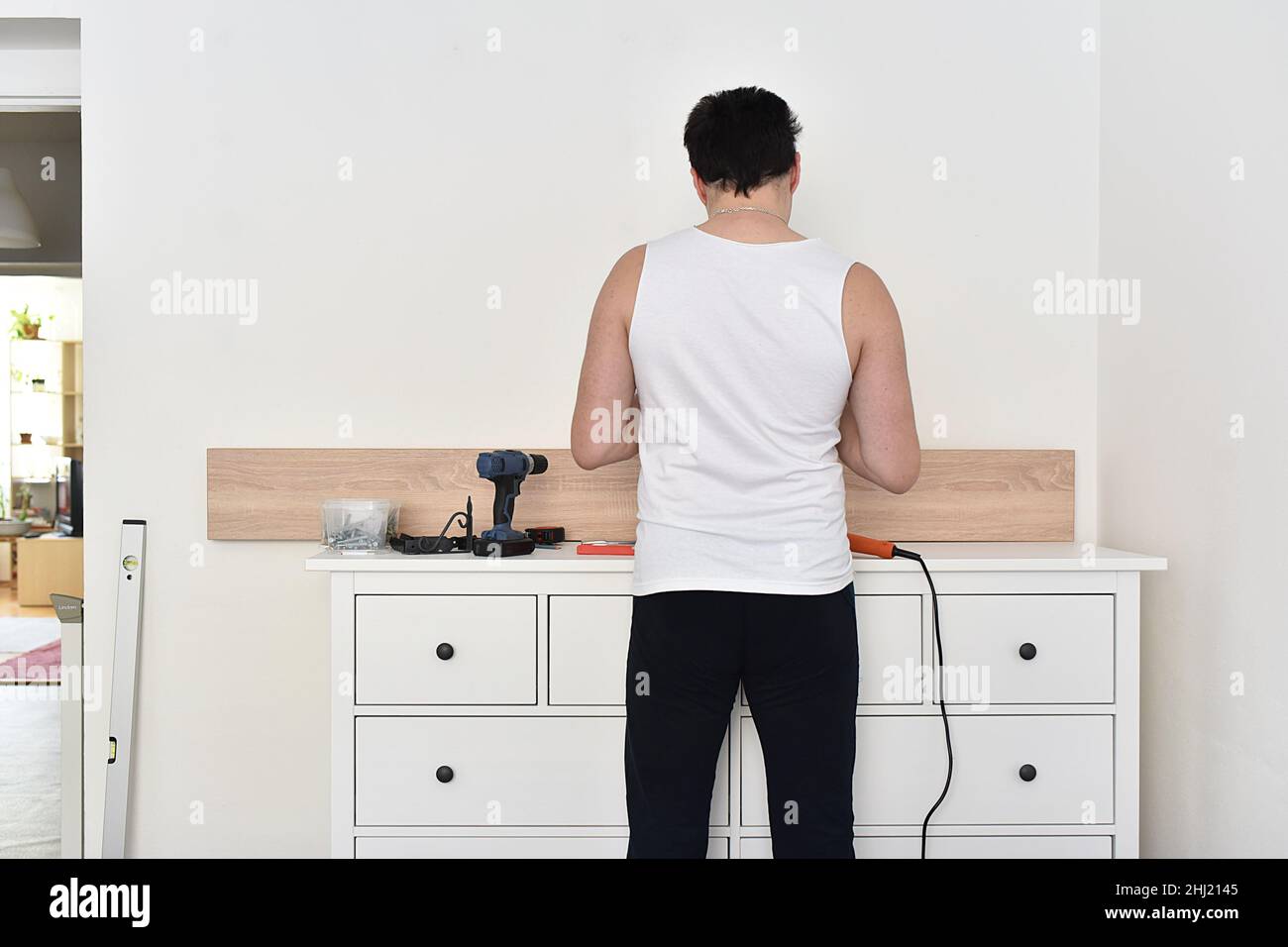 Man mounting shelves on the wall. All necessary tools are placed on the ...