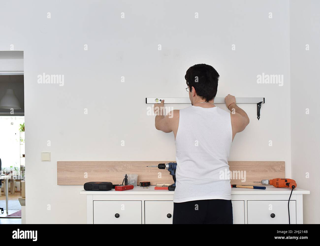 Man measures the spirit level. Wall shelf installation Stock Photo - Alamy