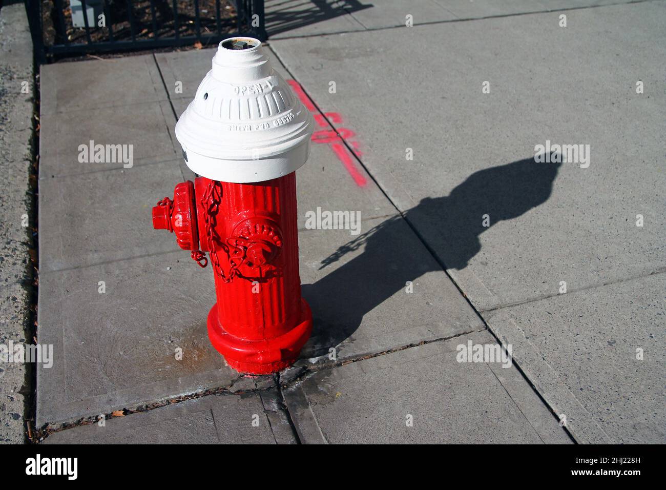 A traditional red and white street hydrant on a concrete outdoors ...