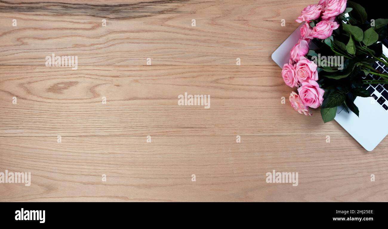 Oak wood office desk table with lovely pink roses on top of a laptop ...