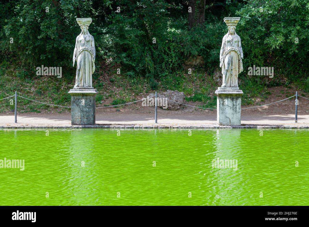 The green water of an ancient swimming pool surrounded by Roman statues ...