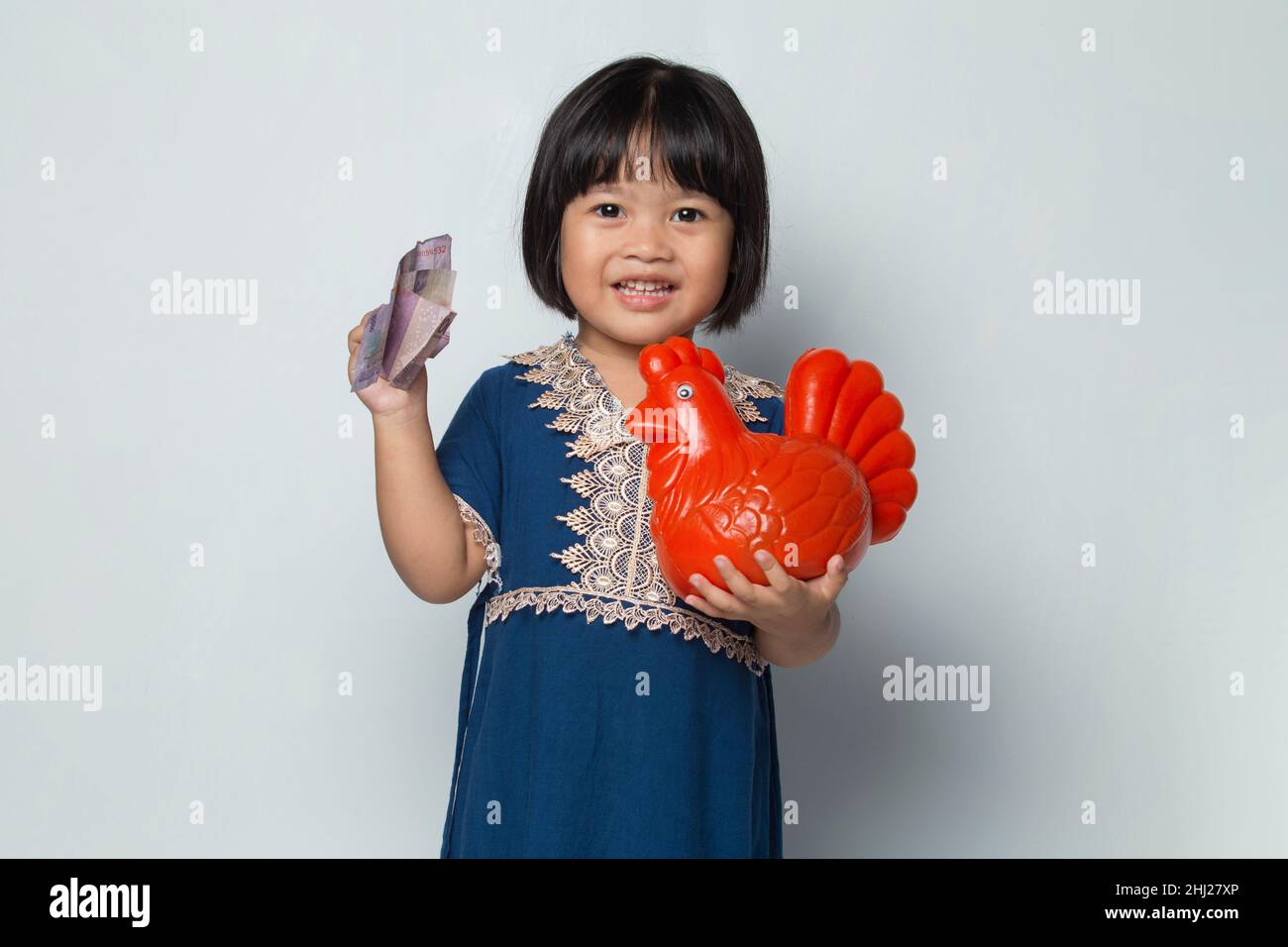 happy little asian girl saving money with a chicken bank isolated on ...