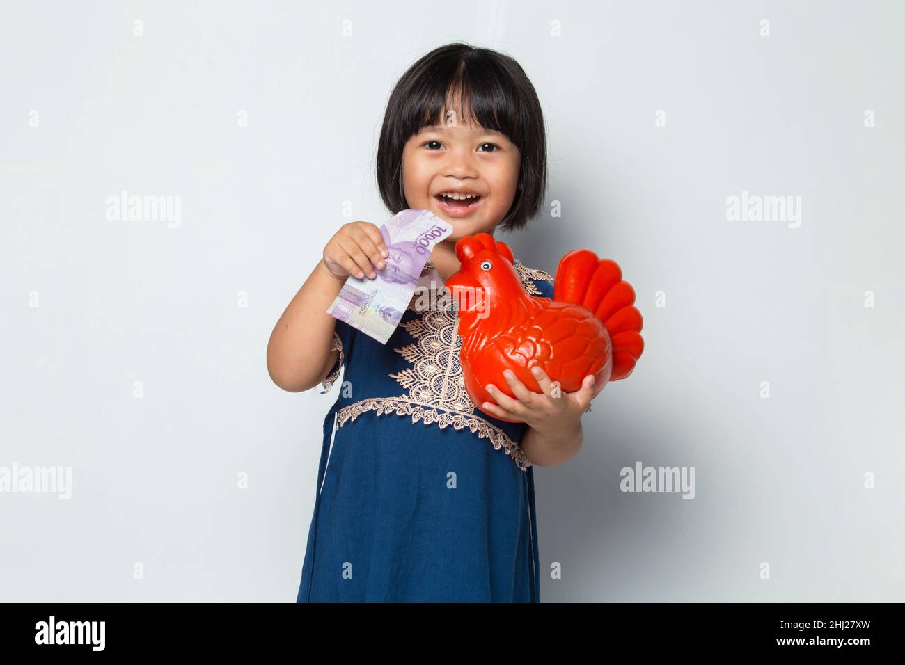 happy little asian girl saving money with a chicken bank isolated on ...