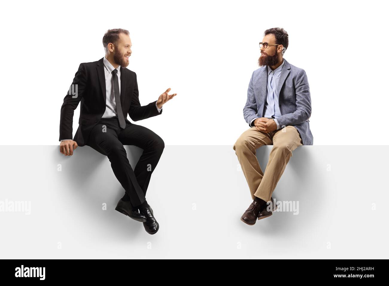 Two professional men sitting on a white panel and having a conversation ...