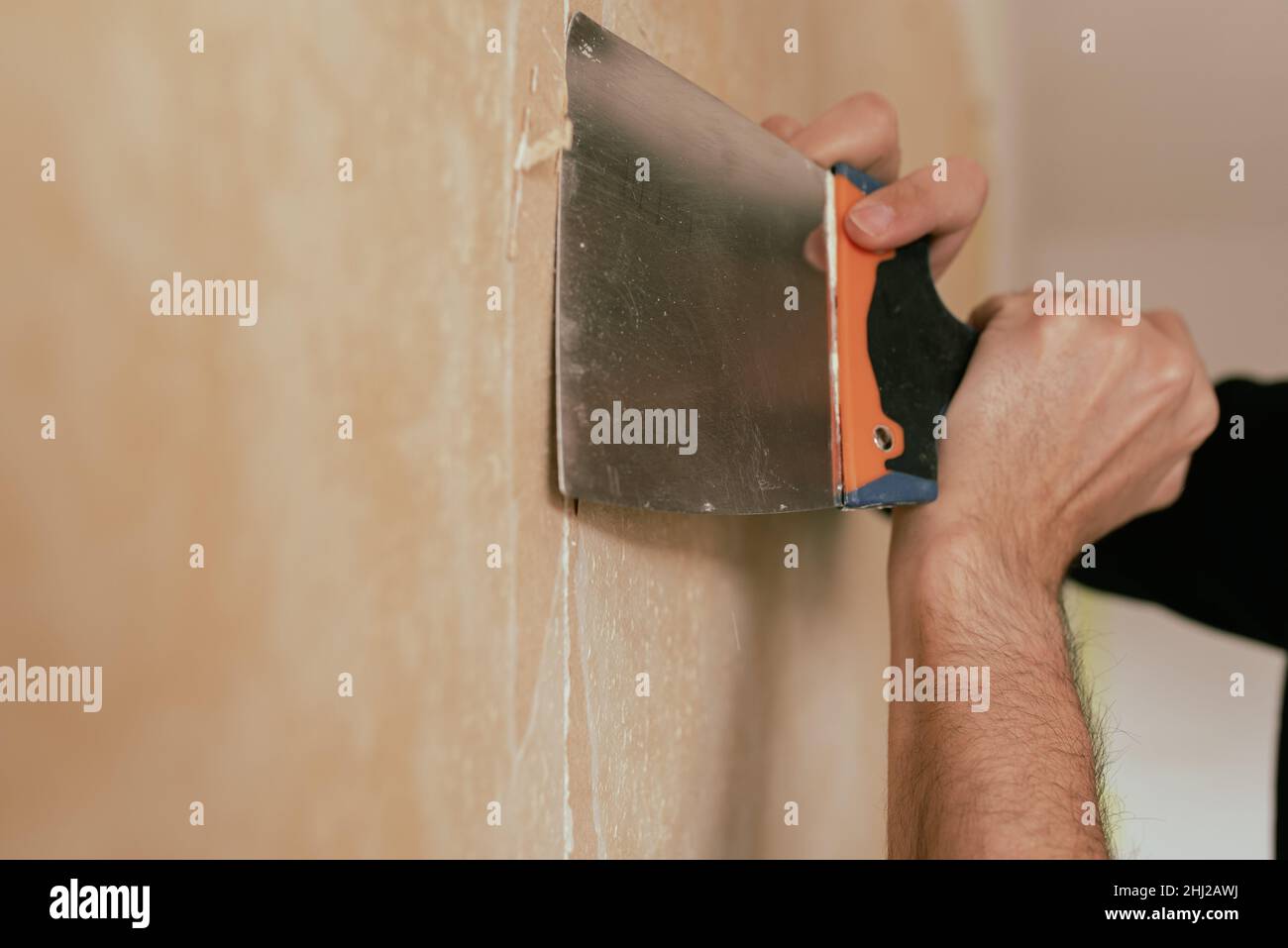 Man hand tearing off old wallpaper with scraper from wall Stock Photo ...