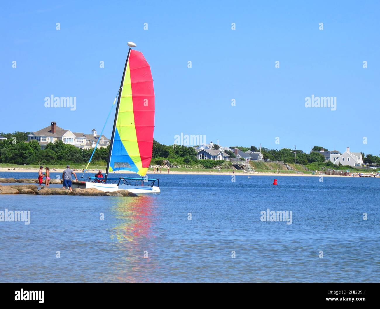 Sailboat with Red,Yellow and Blue sails and blue water and blue sky on ...