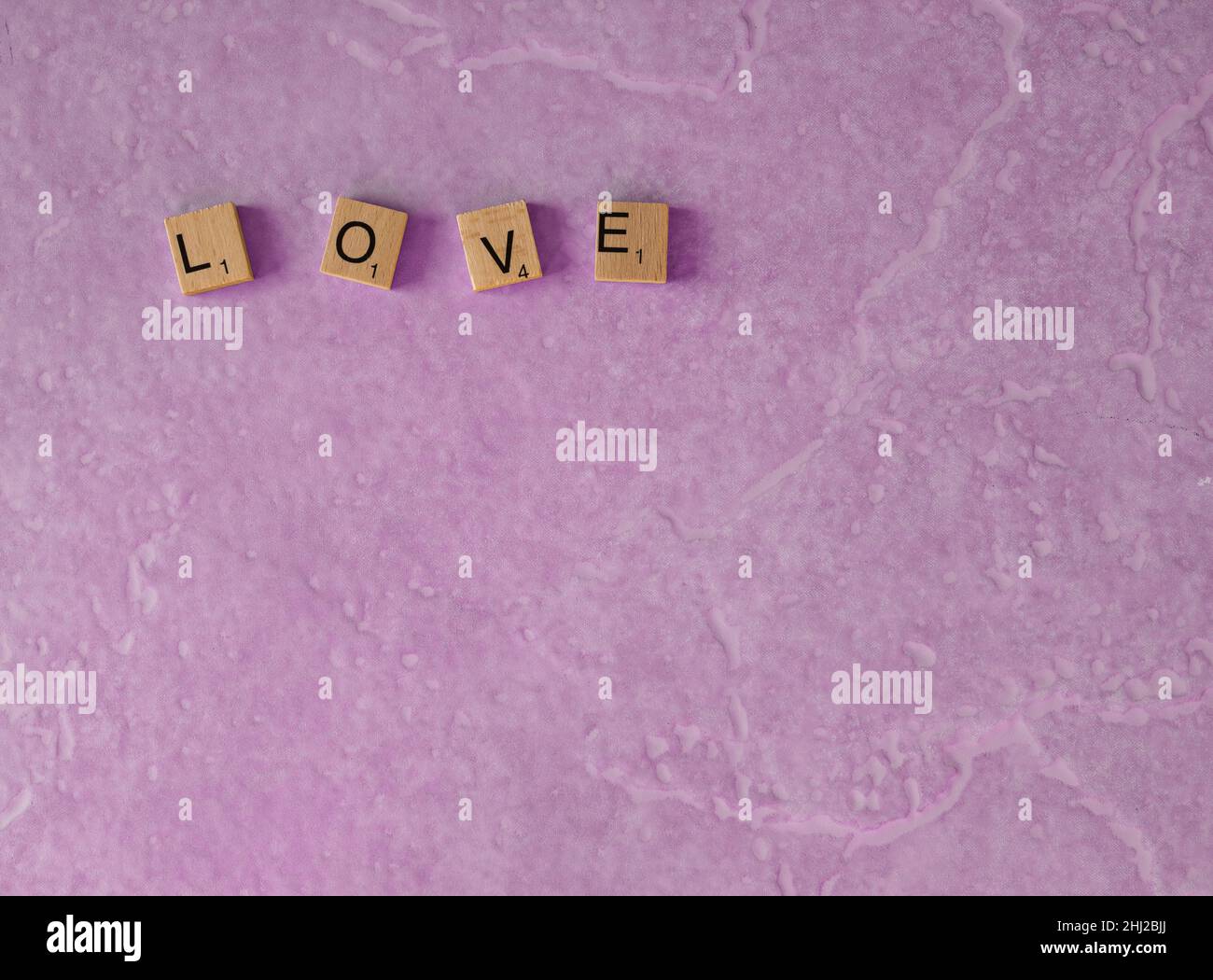 the word love spelt out in wooden squares on a light pink background ...