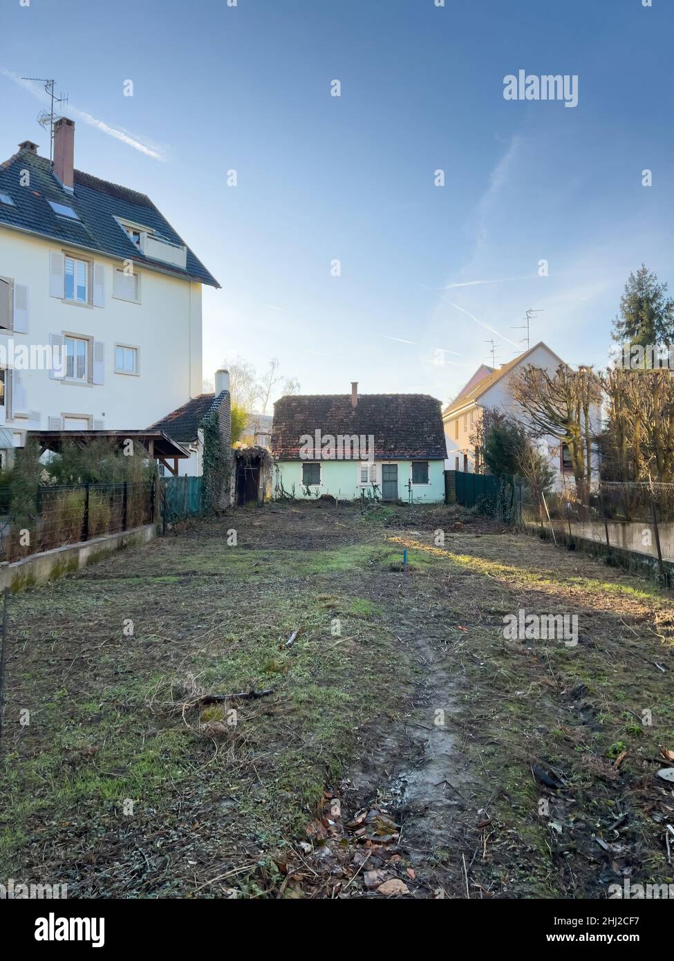 Small abandoned house surrounded by tall apartment building complex ...