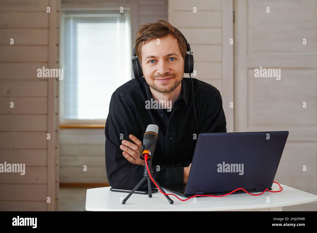 Portrait of influencer podcast creator streaming audio broadcast at his ...