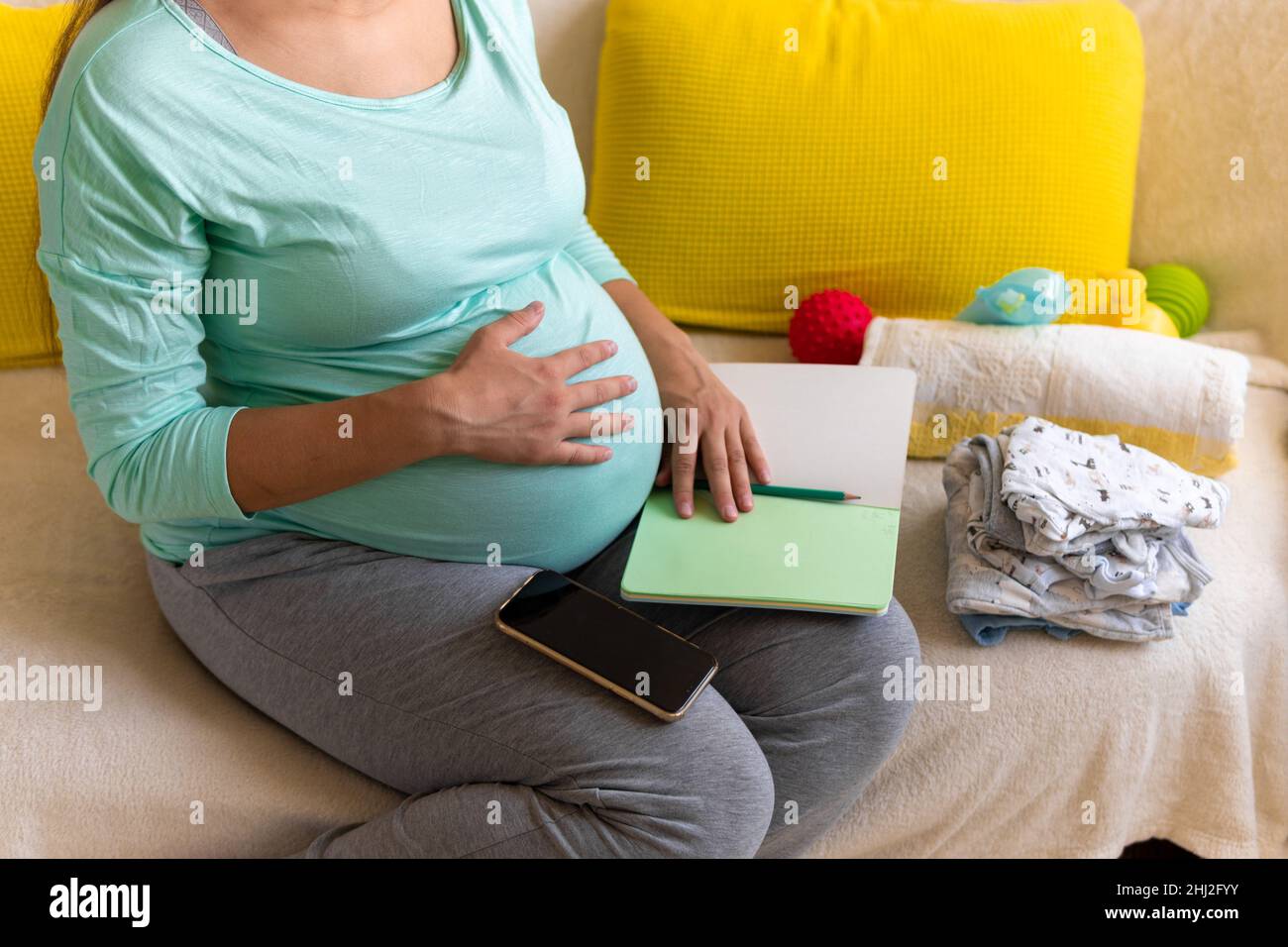 Cute Pregnant Woman writing packing list for maternity hospital With ...