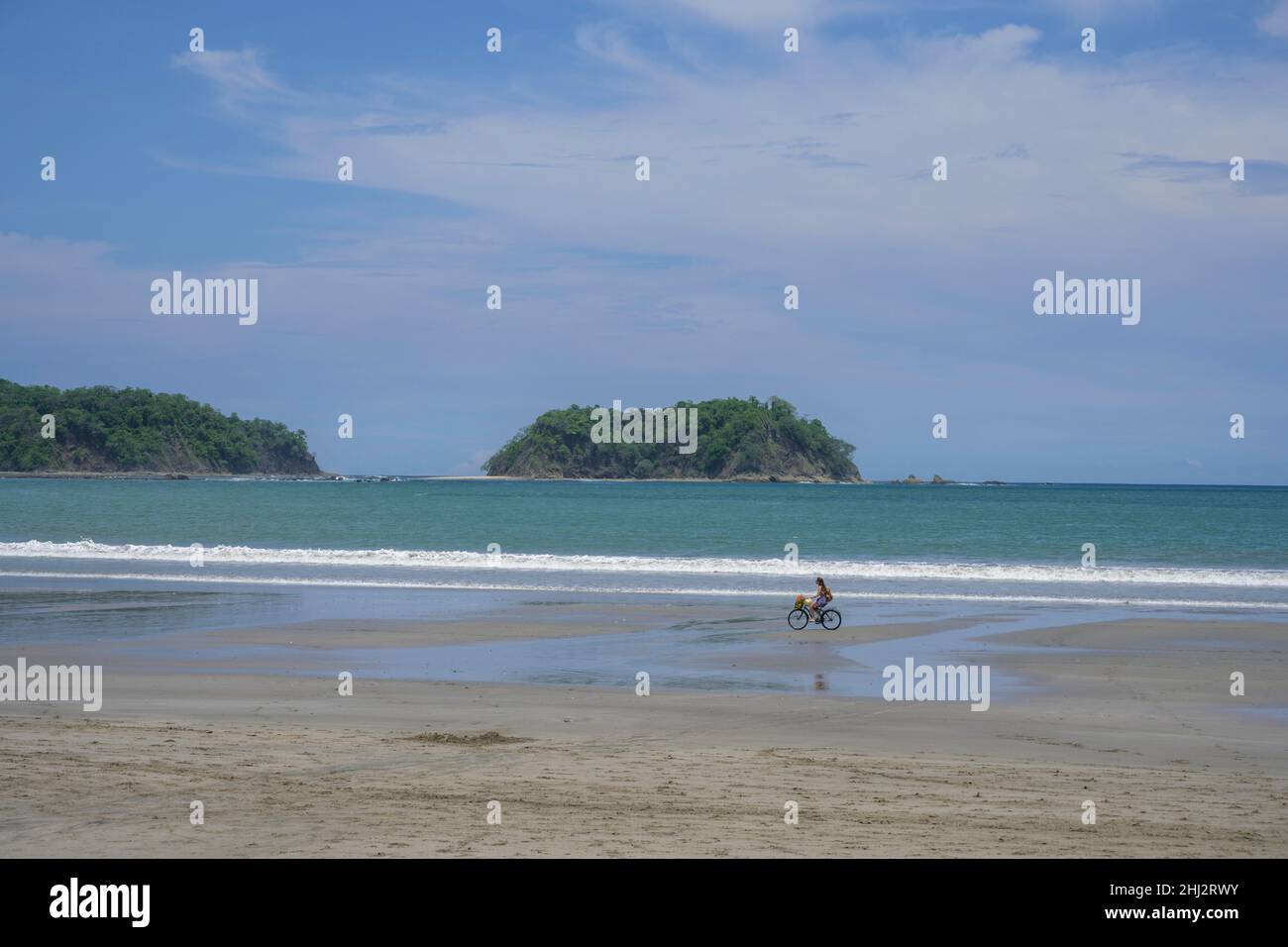 Woman riding a bicycle on the beach of Samara in the background Chora ...