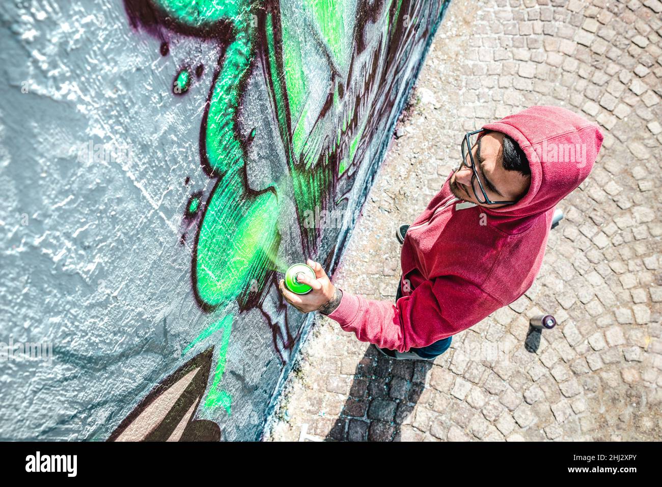 Top view of street artist painting graffiti on generic wall - Modern ...