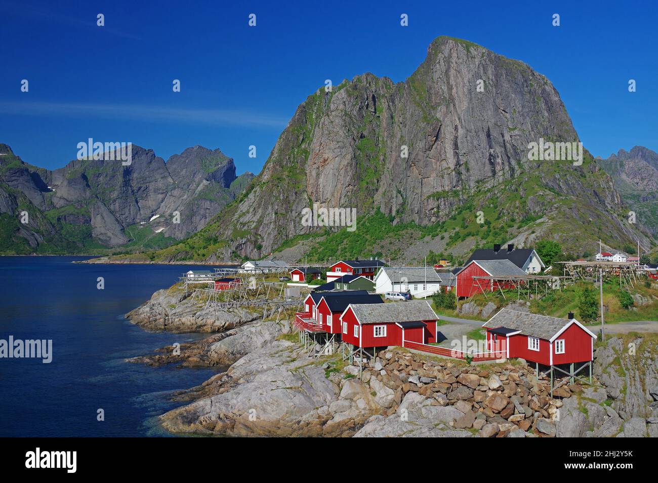 Red Rorbuer on a stony shore, high, rugged mountains, Hamnoey ...