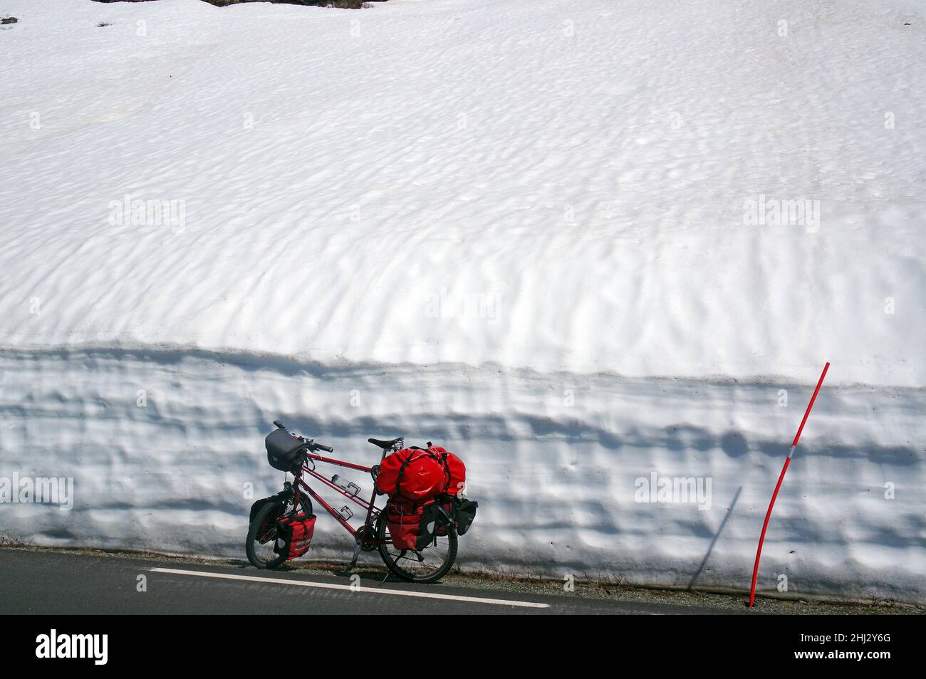 Bicycle with a lot of luggage standing in front of high snow walls ...