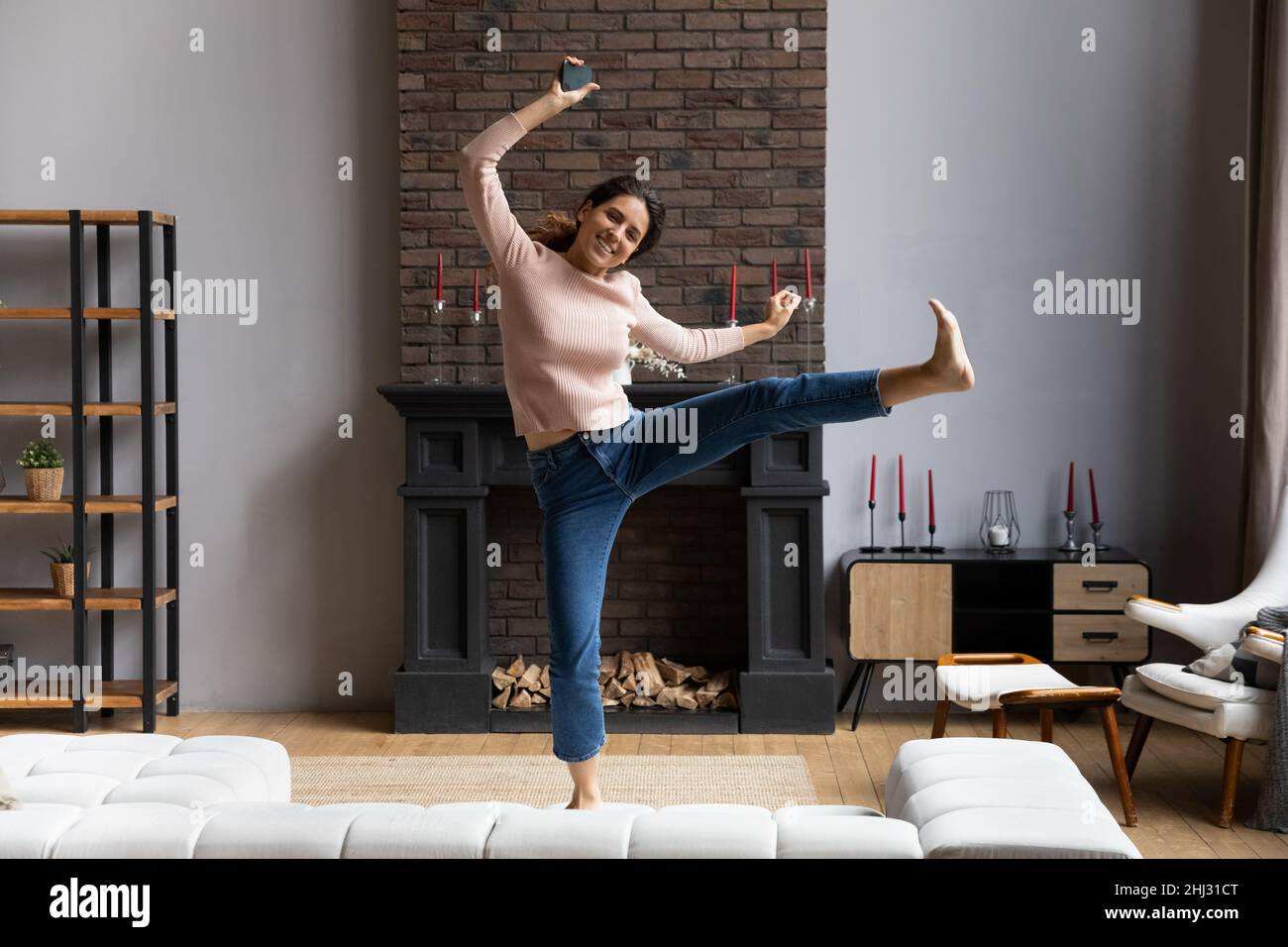 Funny happy woman holds smartphone dancing in living room Stock Photo ...