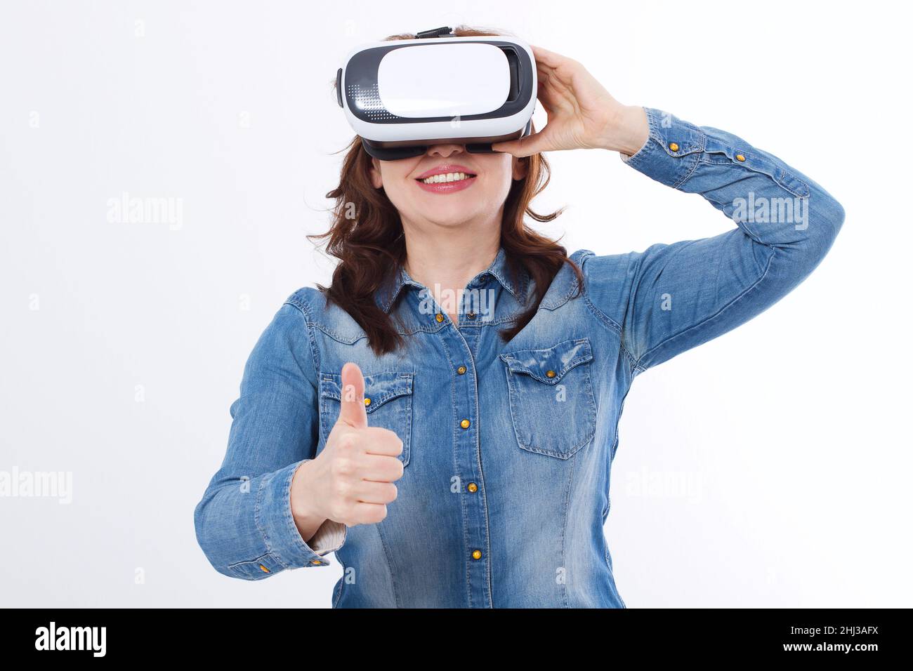 Amazed caucasian woman looking in a VR goggles with big thumb up ...